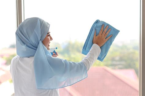 실내 촬영 활동적인 젊은 아름 다운 아시아 주부 여자는 청소 스프레이를 들고 창문 유리를 씻고 있습니다 이사 후 새 아파트에서 행복한 감정적 청소 침실을 가진 귀여운 소녀의