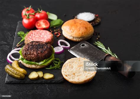 검은 바탕에 빵 양파와 토마토를 곁들인 돌 도마위에 신선한 구운 생 다진 후추 소고기 버거 고기 도끼와 짠 피클과 바질 텍스트를 위한 공간 고기에 대한 스톡 사진 및 기타