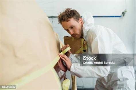 자동 화가 마스킹 차 체에 테이프와 종이 다시 그리기 전에 흰색 보호복을 입은 정비사가 차고에서 작동합니다 25 29세에 대한 스톡 사진 및 기타 이미지 Istock