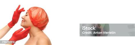 기치 빨간 머리 모자를 쓴 성숙한 여자가 빨간 장갑을 낀 손이 하얀 스튜디오 배경에 얼굴과 턱을 만지면서 웃고 있습니다 50 54세에 대한 스톡 사진 및 기타 이미지