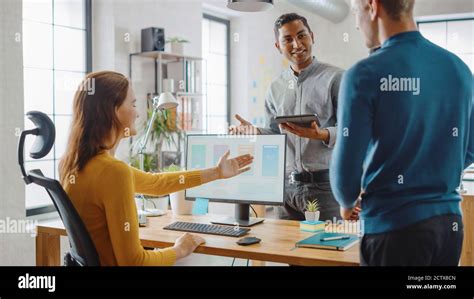 Three Mobile Software Developers Work On Desktop Computer They Discuss Smartphone Application