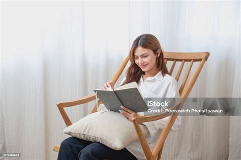 하얀 셔츠를 입고 집 안의 나무 의자에 앉아 노트북에 일기를 쓰고 있는 아름다운 얼굴을 가진 젊은 여성의 초상화 휴식과 휴식의