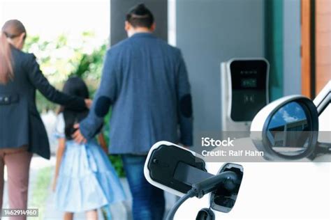 Ev 자동차용 가정용 충전소에 초점을 맞추고 배경에서 진보적인 가족을 흐리게 합니다 3 명에 대한 스톡 사진 및 기타 이미지 3 명 가리키기 가족 Istock