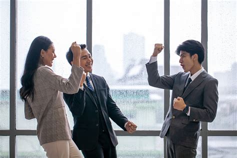 아시아 비즈니스 팀은 사무실에서 기업의 승리를 함께 축하하고 웃고 기뻐하며 사무실에서 기쁨으로 비명을 지르는 흥분한 직원 동료들을 웃습니다 Teamwork Makes The