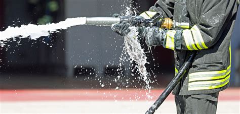 소방관이 보호 장구를 착용한 상태에서 화재를 진압하기 위해 호스에서 거품제를 분사하는 모습 긴급서비스와 구조 직업에 대한 스톡 사진 및 기타 이미지 긴급서비스와 구조