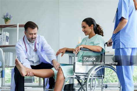 남성 정형외과 의사가 휠체어를 탄 스페인 여성 환자의 다리를 들어 올리고 있다 다리를 위아래로 들어 올려 부상 여부를 확인합니다 물리 치료사와 함께 물리 치료를 준비합니다