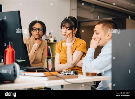 Focused Computer Programmers Looking At Laptop While Working Together