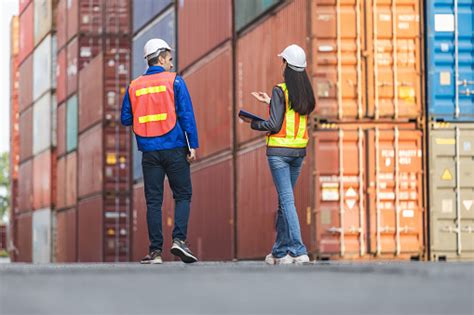 클립보드를 사용하는 여성 감독 안전 조끼 체크리스트와 안전모를 쓴 노동자 남자가 화물에서 컨테이너 상자를 적재하기 위해 태블릿을 들고 있습니다 2명에 대한 스톡 사진 및