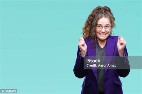 교 복을 입고 젊은 갈색 머리 학생 소녀와 무기와 성공에 대 한 흥분된 격리 된 배경 위에 안경 승리 축 하 하 웃는 발생 합니다 우승자 개념입니다 곱슬 머리에 대한 스톡