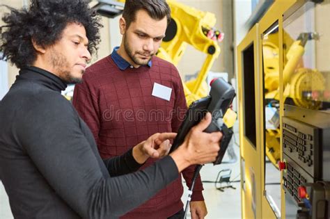 Engineers Programming Industrial Robot With Control Panel For Precision