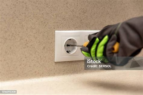 전기 콘센트 설치 전기 기술자는 전기 콘센트에 장식 프레임을 설치합니다 장갑이 달린 소켓을 설치하는 마스터의 손에 드라이버