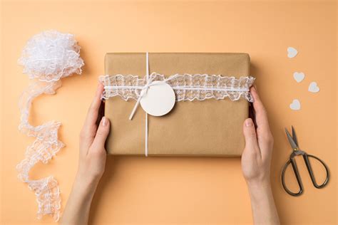 1 인칭 탑 뷰 사진 세인트 발렌타인 데이 장식 소녀의 손은 레이스 리본 트림과 카피 스페이스와 고립 된 베이지 색 배경에 레이스 하트의 태그 가위 스풀과 크래프트 종이