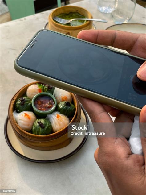 대나무 찜기에 섞인 미식가 모모를 중앙에 소스 냄비 조개 모양 양배추 잎 만두 인기 있는 인도 길거리 음식 소셜 미디어 사진 높은 전망 사진을 찍는 스마트폰 기기의 이미지