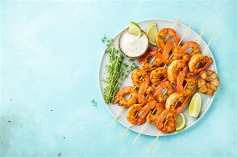 그릴에 구운 새우 꼬치 또는 랑구스틴과 라임 마늘 소스를 연한 파란색 콘크리트 배경에 얹어 드실 수 있습니다 해산물 복사 공간이 있는 맨 위 뷰입니다 플랫 레이 갑각류에