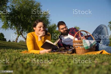 녹색 잔디에 누워 미소와 매력적인 아름 다운 커플의 초상화는 풍경을 통해 외부 함께 시간을 즐기는 과일과 바구니를 가진 목가적인 하모니 백 일 몽 개념 2명에 대한 스톡