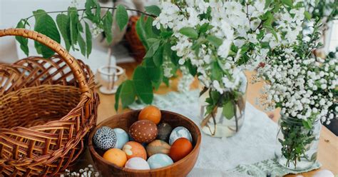 부활절 달걀 천연 염색 부활절 빵 케이크 햄 버터 녹색 가지 고리 버들 바구니와 촛불이 있는 소박한 나무 테이블에 꽃 교회에서 축복을위한 전통 부활절 음식 사진