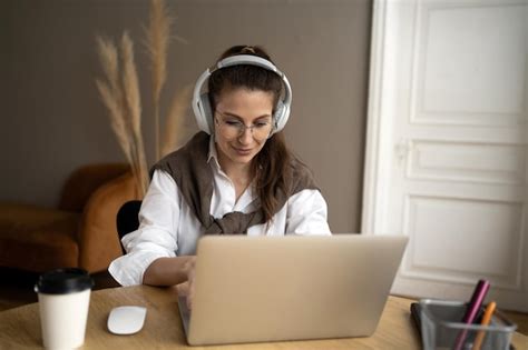 Premium Photo A Woman With Headphones A Programmer With Glasses In The Office Uses A Laptop