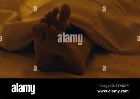 Close Up Of Female Feet Under Blanket Girl Sleeping In Bed At Night