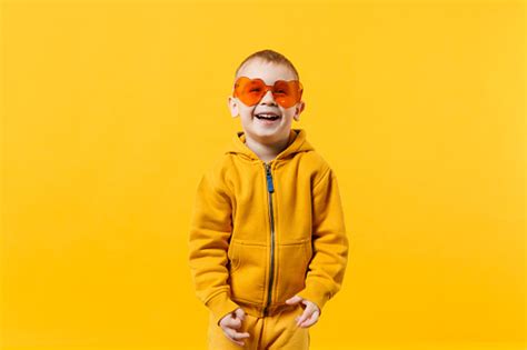 귀여운 꼬마 소년 34 년 된 노란색 옷을 입고 밝은 오렌지 벽 배경 어린이 스튜디오 초상화에 고립 사람들이 진심으 감정 어린 시절 라이프 스타일 개념 복사 공간을 비웃는