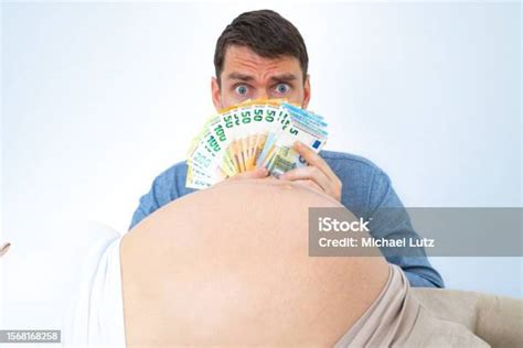 임신한 아기 범프 뒤에 있는 임산부는 지폐 더미를 얼굴 앞에 들고 걱정스러운 표정을 짓고 있습니다 임신 마지막 달 39 주 흰색 배경입니다 밝은 샷 2명에 대한 스톡 사진