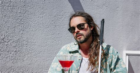 긴 머리와 선글라스를 쓴 남자가 음료를 들고 있다 사진 Unsplash의 눈 먼 이미지