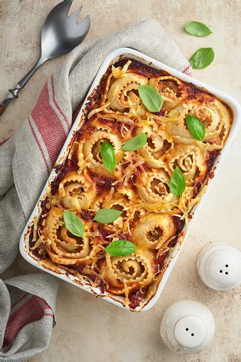 라자냐 수제 라자냐 파스타 로톨로는 가벼운 슬레이트 돌 또는 콘크리트 배경의 흰색 프라이팬에 토마토 소스 크림 치즈 및 바질로