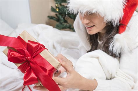 즐거운 휴일 보내세요 여성의 손은 흰색 침대에서 크리스마스 선물 상자에 활을 풀어 2 5 개월에 대한 스톡 사진 및 기타 이미지 2 5 개월 가정의 방 겨울 Istock