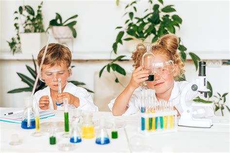 실험실에서 화학 실험을 수행하는 흰색 유니폼을 입은 진지한 어린 소년과 소녀 학교 개념으로 돌아 가기 젊은 과학자 자연과학