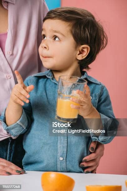 신선한 오렌지 주스의 전체 유리를 들고 있는 귀여운 꼬마 소년과 식탁에 서 있는 동안 모자를 보면 2명에 대한 스톡 사진 및 기타 이미지 Istock
