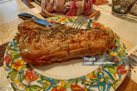큰 쇠고기 스테이크를 요리 하 고 로즈마리와 함께 양념 여전히 접시에 흡연 나이프와 포크는 슬라이스 할 준비가 되어 있습니다