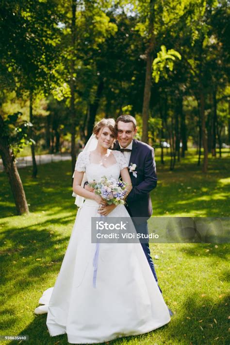 아름 다운 결혼식 Photosession입니다 블루 정장 양복과 그의 우아한 신부 드레스와 베일 화창한 날에 큰 녹색 공원에서 산책에 아름 다운 Hairdress 포옹과