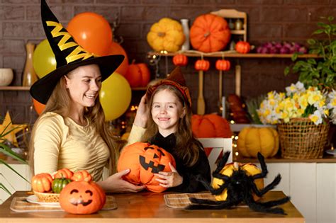 할로윈 어두운 부엌에서 호박과 큰 거미와 마녀 의상을 입은 아이의 어머니와 딸은 할로윈 휴일을 웃고 기뻐하며 축하합니다 25 29세에 대한 스톡 사진 및 기타 이미지