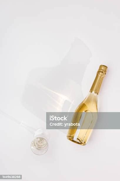 상위 뷰 화이트 스파클링 와인 병과 밝은 흰색 배경에 태양 그림자와 눈부심이 있는 유리 와인 평평한 황금 샴페인 병 축제 여름 알코올 음료 개념 트렌디 한 정물 개념에 대한