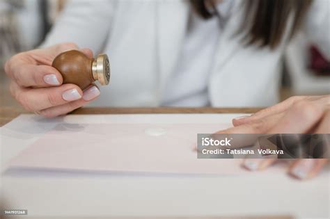 나무 책상에 있는 흰색 엽서 봉투에 스탬프가 찍힌 흰색 왁스 씰을 만드는 여성의 잘 손질된 손의 자른 사진 Diy에 대한 스톡 사진 및 기타 이미지 Istock