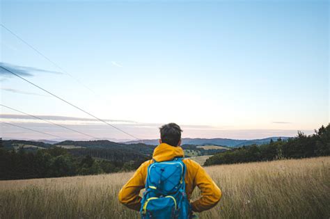 노란색 재킷에 파란색 배낭을 메고 체코 베스키디 산맥의 석양과 평화로운 풍경을 내려다보는 등산객 사색과 자연이 어우러진 조용한 순간 25 29세에 대한 스톡 사진 및 기타