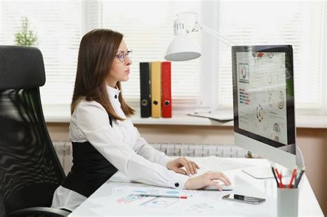 Красивая деловая женщина в костюме и очках работающая за компьютером с