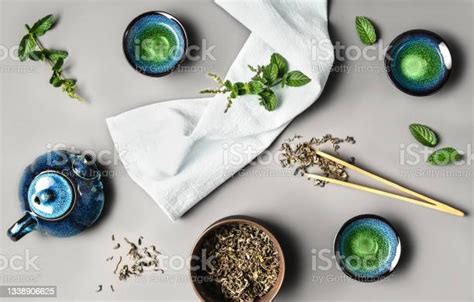 짙은 파란색 점토 주전자와 민트 잎 장식과 흩어진 차와 회색 배경에 작은 컵에 녹차 플랫 레이 스타일 잎차에 대한 스톡 사진 및 기타 이미지 Istock
