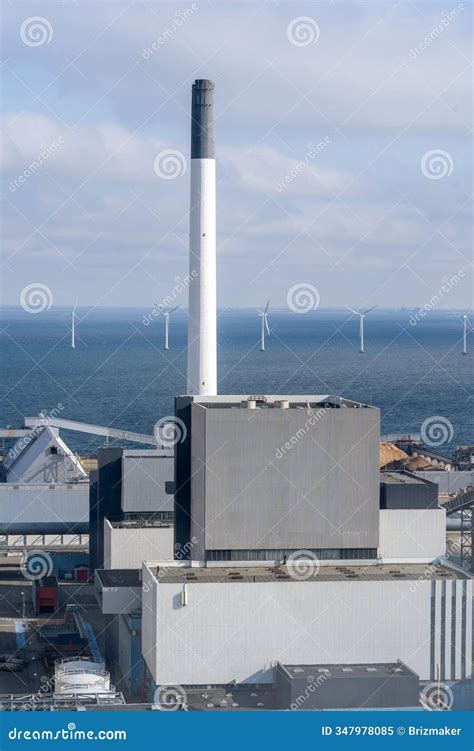 Industrial Complex With Tall Chimney And Offshore Wind Turbines Royalty