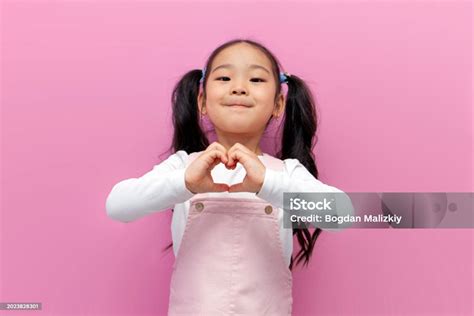 긴 머리에 분홍색 선드레스를 입은 아시아 소녀는 손으로 마음을 보여주고 한국 미취학 아동은 사랑의 제스처를 취합니다 아이에 대한 스톡 사진 및 기타 이미지 Istock