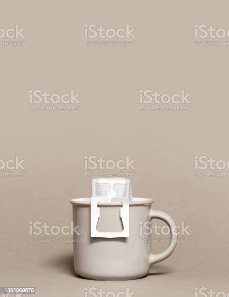 큰 컵에 분쇄 커피와 드립 커피 가방 베이지 색 배경에 양조를위한 종이 가방 드립 커피 필터 패키지 복사 공간 흑백 색상 측면보기 Robusta Coffee Drink에