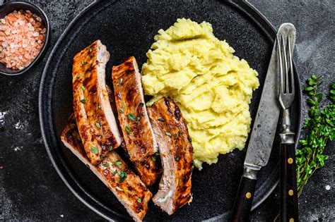 으깬 감자를 곁들인 접시에 얇게 썬 바베큐 그릴 돼지 고기 랙 예비 갈비 검은 색 배경 위쪽 보기 갈비 음식에 대한 스톡 사진 및 기타 이미지 Istock