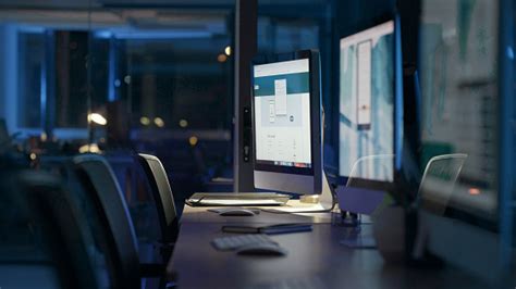 조용한 빈 작업장 내부의 테이블 위에 서있는 데스크톱 컴퓨터 화면과 키보드 관리자는 업무 시간 후 의자와 닫힌 책을 밤늦게까지 테이블에 놓고 사무실 공간을 일합니다 0명에