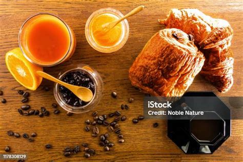 초콜릿 빵과 순수 버터 크루아상 꿀 항아리와 딸기 잼이 있는 소박한 나무 테이블에 에스프레소 커피 한 잔과 수제 압착 오렌지
