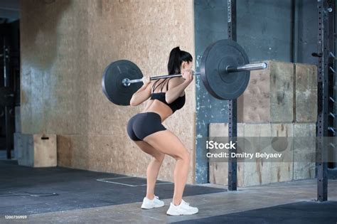 체육관에서 바벨과 함께 운동하는 동안 여성의 사이드 백 사진은 무게를 들어 올리고있다 선반 제작물에 대한 스톡 사진 및 기타