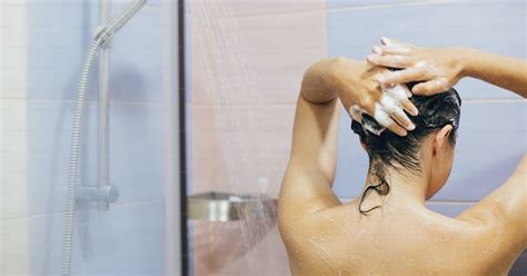 젊은 행복한 여자는 샴푸로 머리를 씻고 손으로 거품을 낸다 샤워를 하고 휴식 시간을 즐기는 아름다운 갈색 머리 소녀 몸