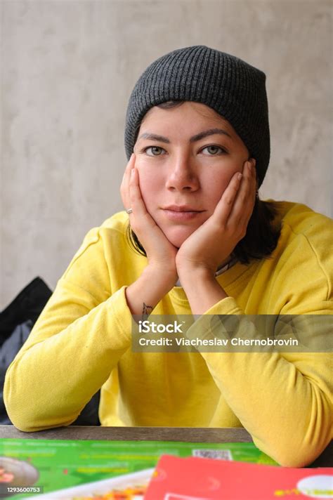 니트 모자와 노란 스웨터를 입은 귀여운 젊은 여성이 카페의 테이블에 앉아 두 개의 접힌 손에 머리를 얹습니다 가을에 대한 스톡 사진 및 기타 이미지 Istock