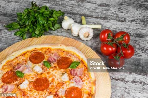 살라미 베이컨 치킨 토마토 소스와 로즈마리 밝은 나무 배경에 향신료와 얇은 피자 신선한 야채와 녹색 바 질 배경 이탈리아 피자