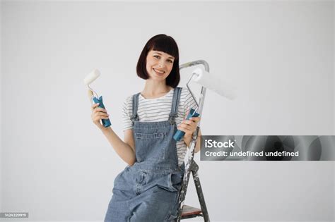 30 세의 아름다운 젊은 여성 사다리에 앉아서 페인트 롤러와 브러시를 손에 들고 페인트 롤러에 대한 스톡 사진 및 기타 이미지 페인트 롤러 여성 여자 Istock