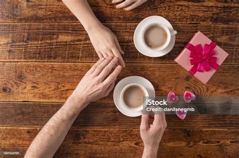 발렌타인 데이 축하 개념입니다 사랑하는 사람을위한 좋은 선물 나무 테이블 배경에 커피 잔과 남자와 여자의 손 공간을 복사합니다