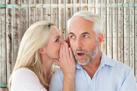 Premium Photo Woman Whispering A Secret To Husband Against Wooden Background In Pale Wood